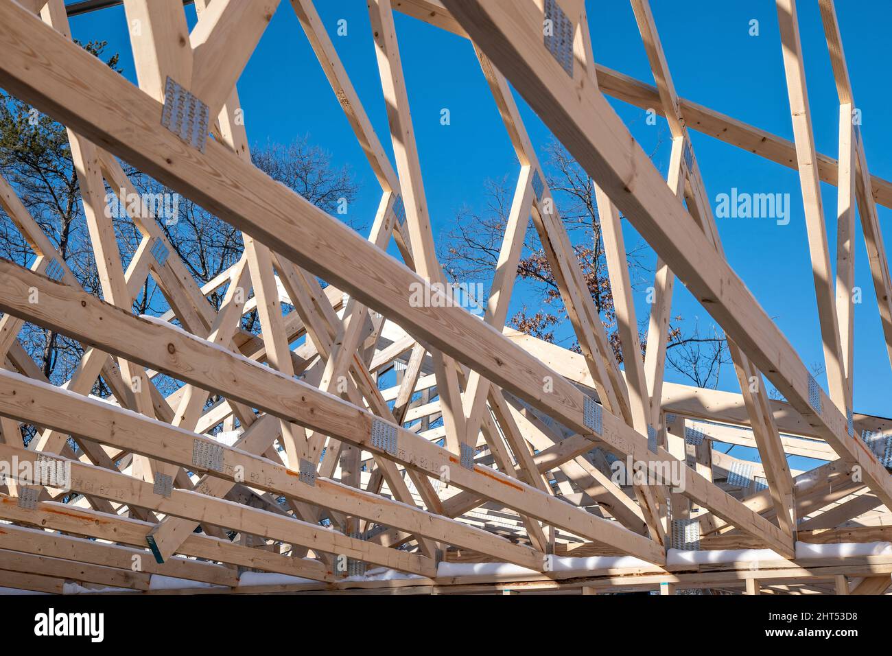 Many wooden roof trusses on a new home construction project with blue ...