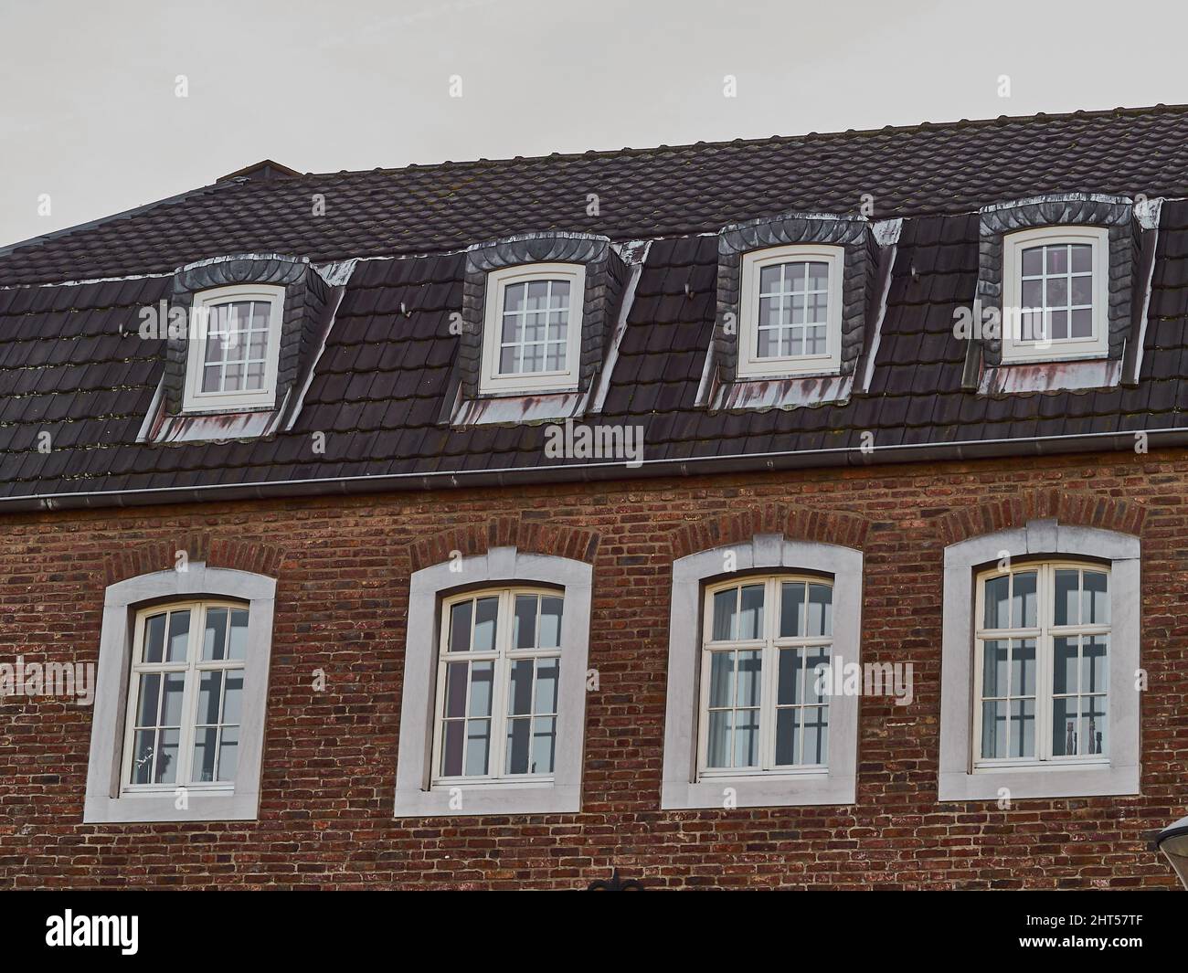 Old building brick facade and roof white windows on a background of sky ...