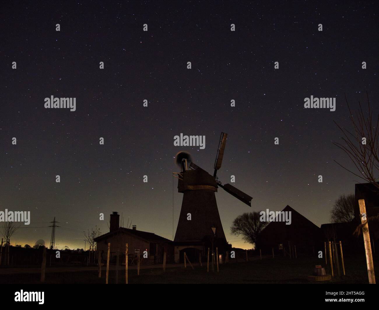 Eerie scenery of a windmill in a rural area witha starry night sky ...