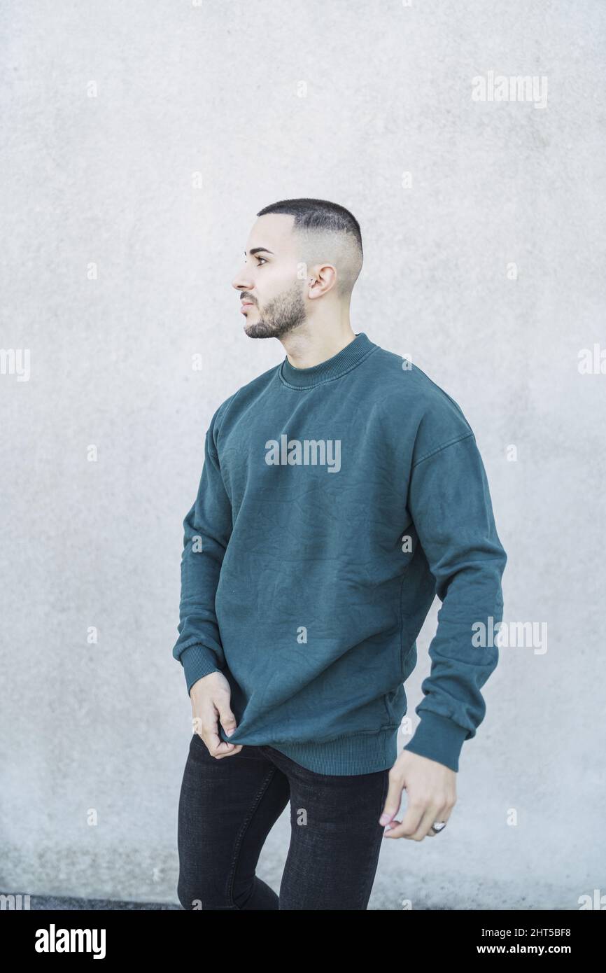 Handsome Spanish man with buzz cut wearing a blue sweater outdoors ...