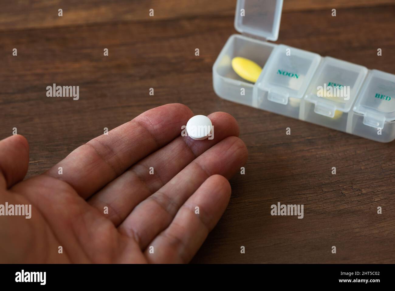 A tablet of medication on hand. Drug container dividing according to ...