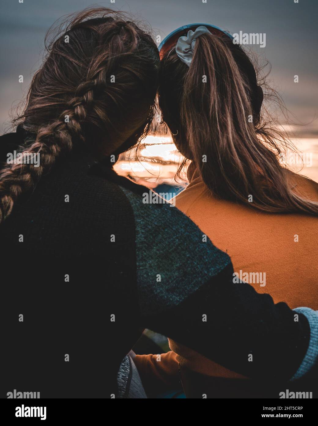 Vertical shot of two sisters hugging each other while enjoying the ...