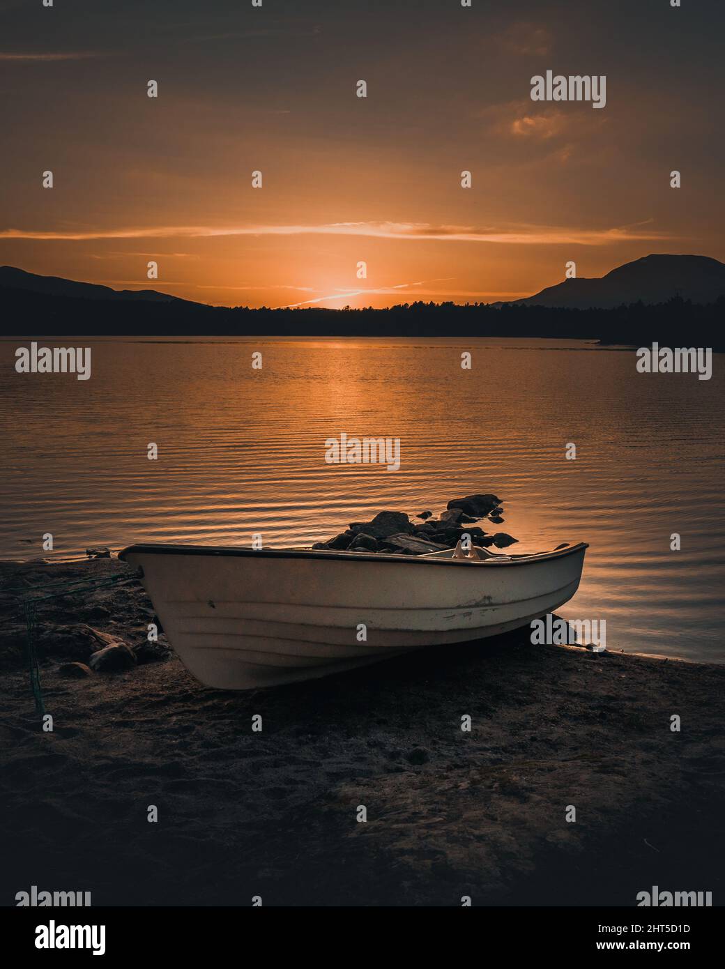 Beautiful scenery of a sunset over a pure lake with a white small boat ...