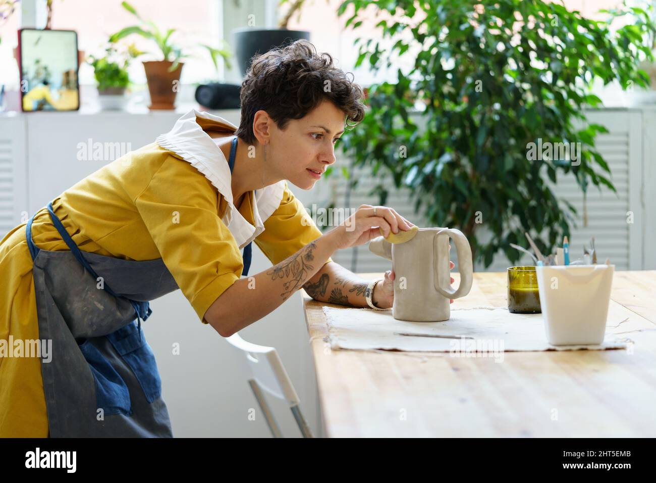 Young girl artisan busy with modeling jug from raw clay while pottery ...
