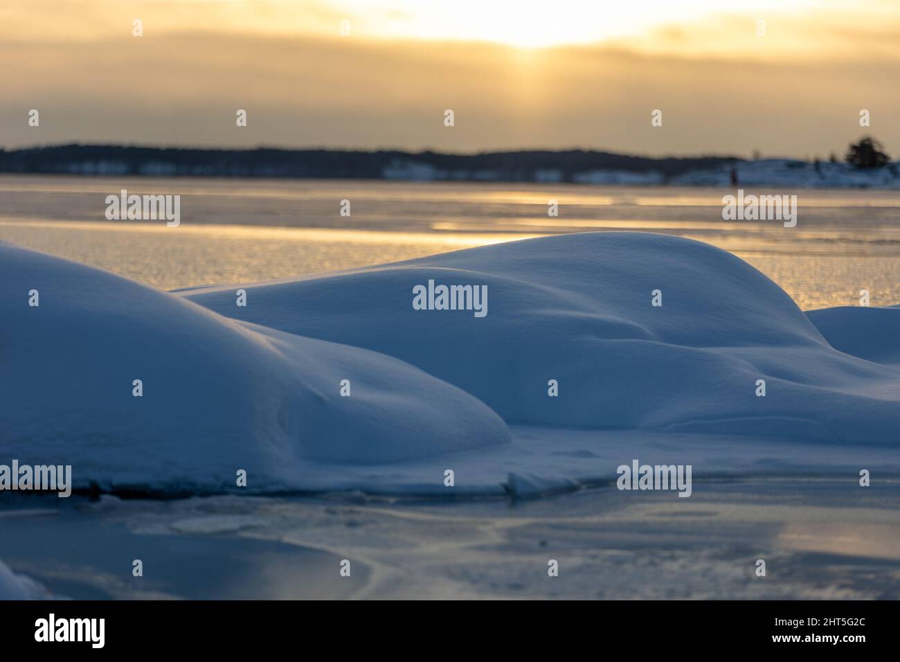 Beautiful winter beach covered in snow with the sun rays shining over ...