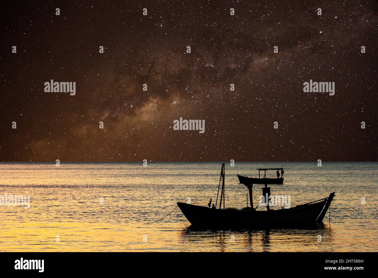 Silhouette of a boat in the sea with the Milky Way in the sky ...
