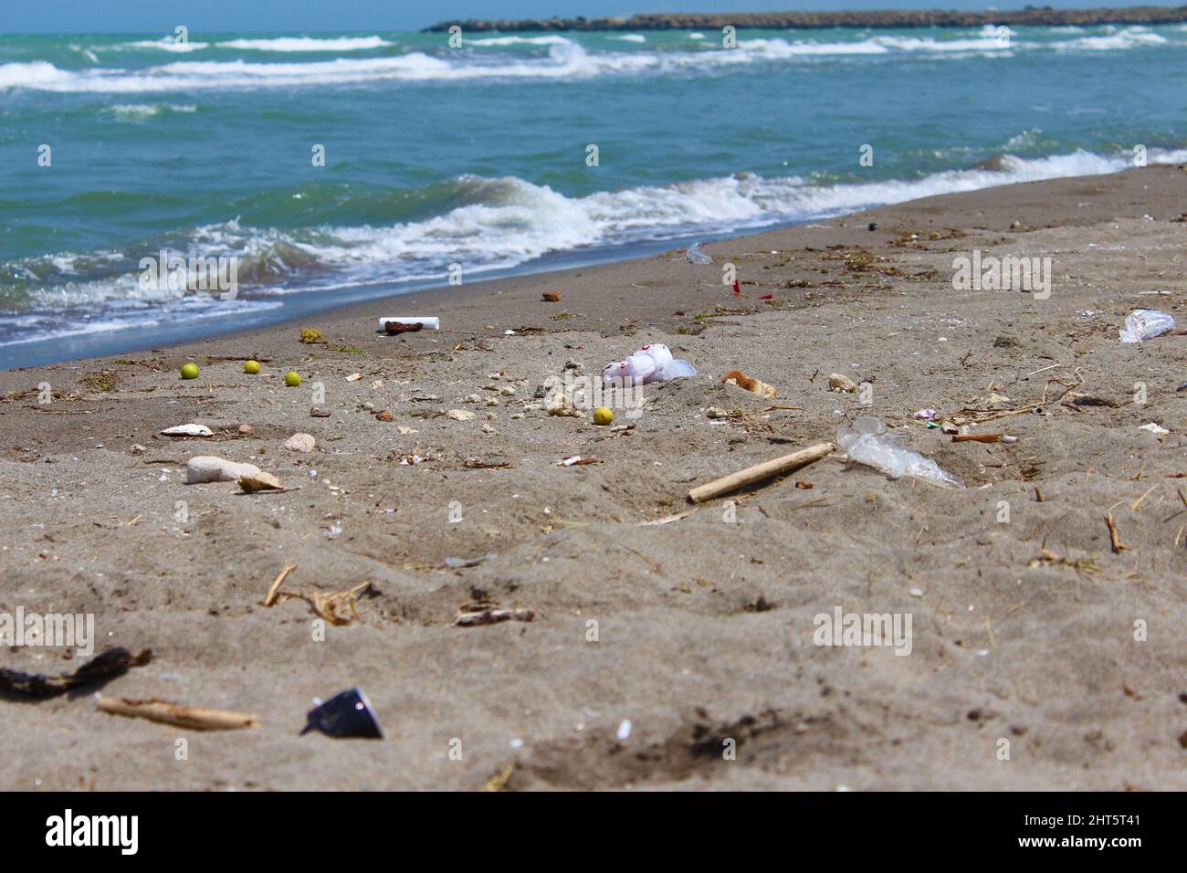 Closeup shot of trash on a beach near the blue sea water, environmental ...