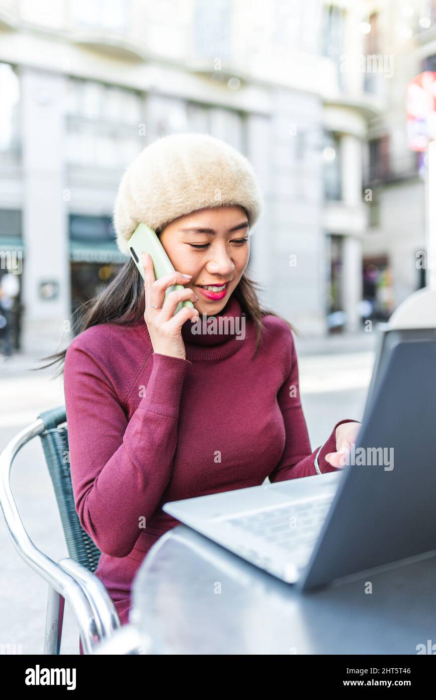 Positive Chinese female having phone conversation while surfing ...