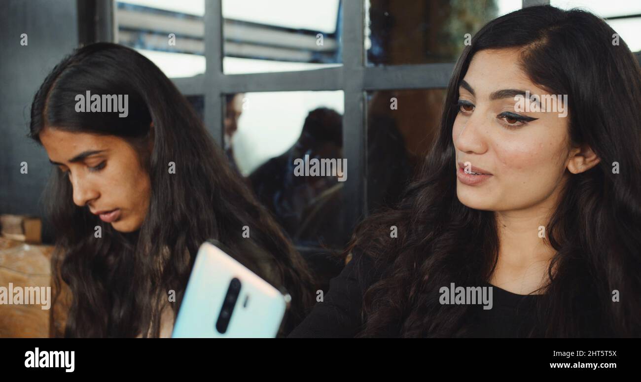 Beautiful young South Asian woman using smartphone indoors next to a ...
