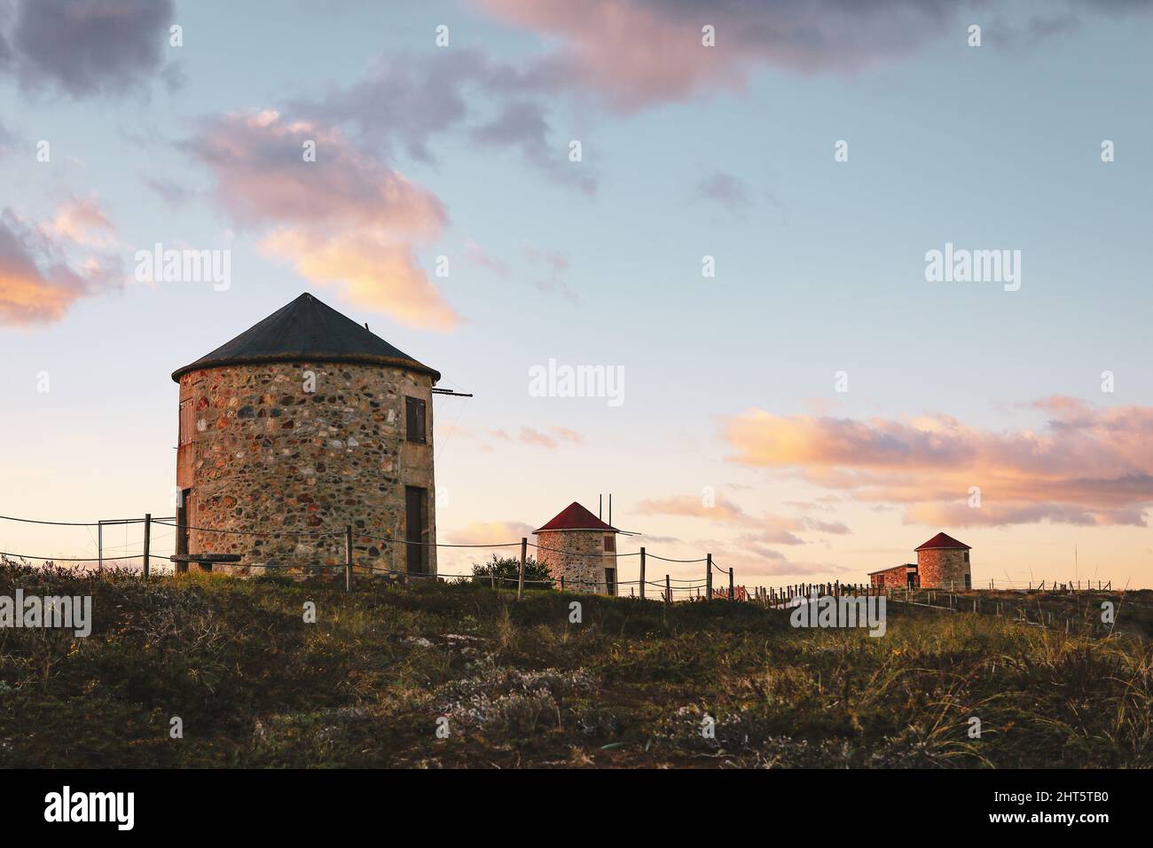 Scenic view of old round stone buildings in a green open field at pink ...