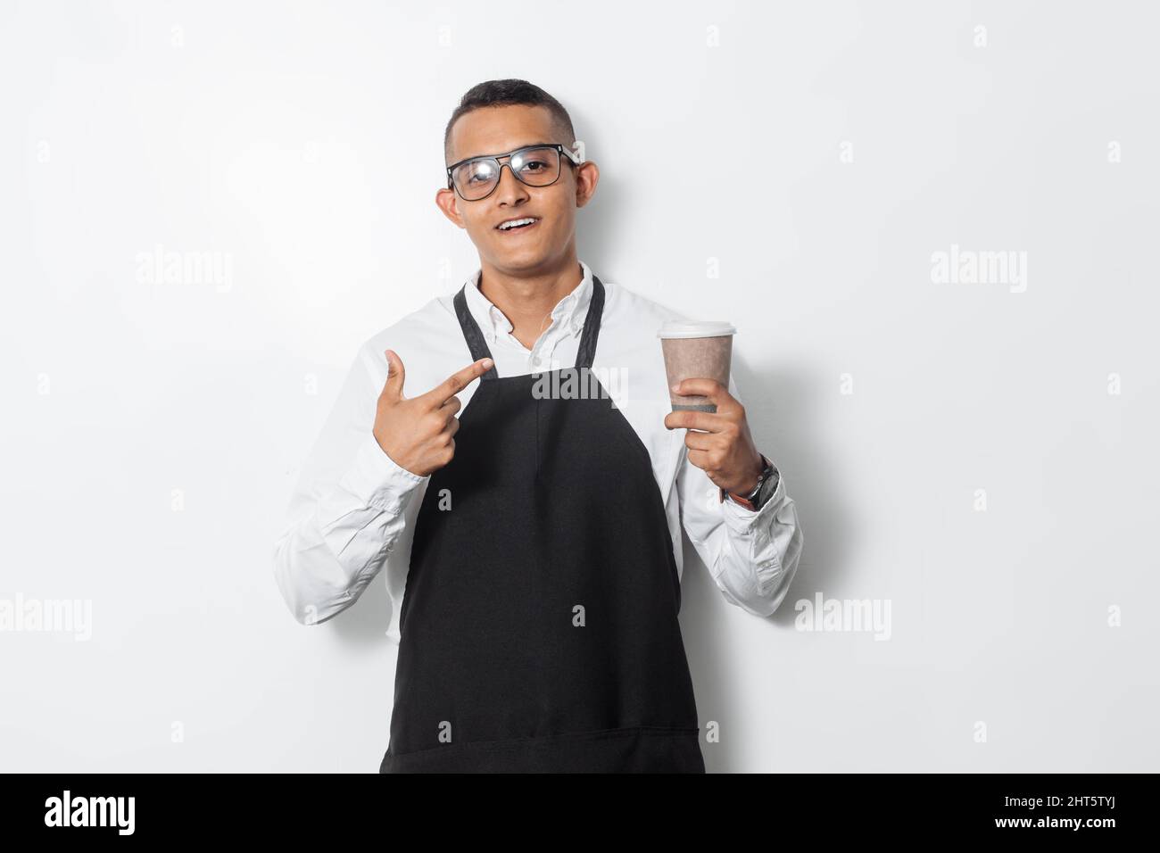 Latin American man pointing finger at coffee cup near the white wall ...