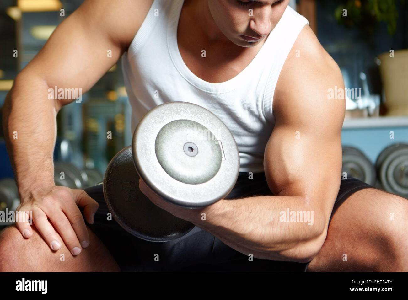 Working on his arms. Cropped shot of a muscular young man working out ...