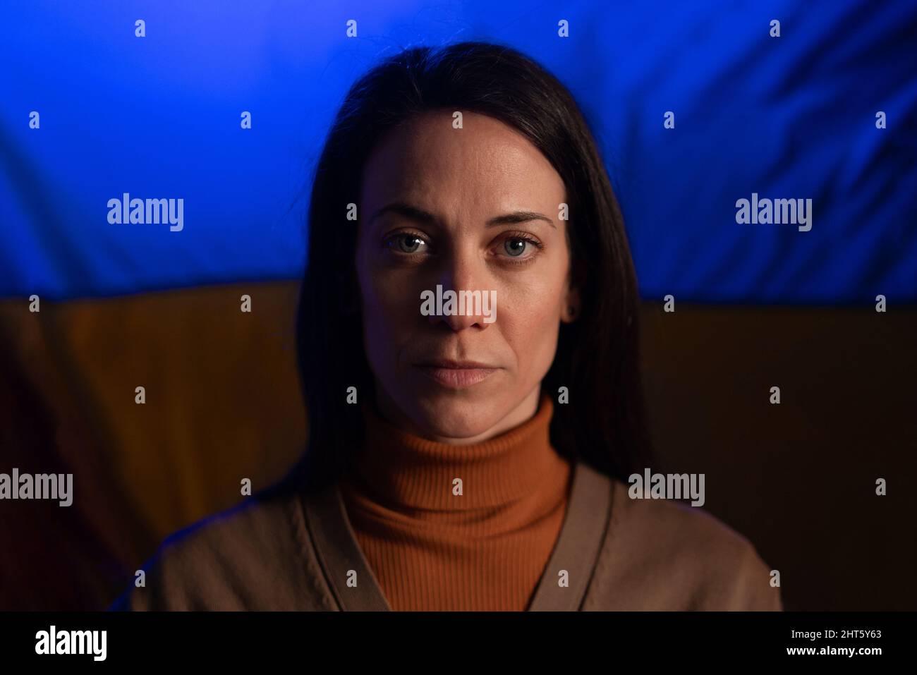 Sad woman with Ukraine flag at background looking at camera. Concept of ...