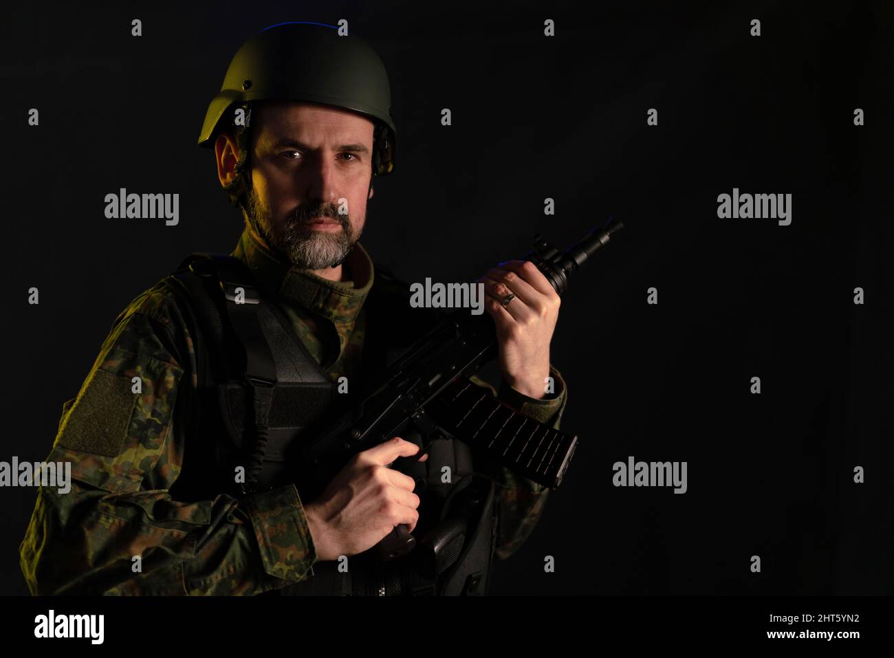 Soldier in military uniform and helmet with weapon looking at camera on ...
