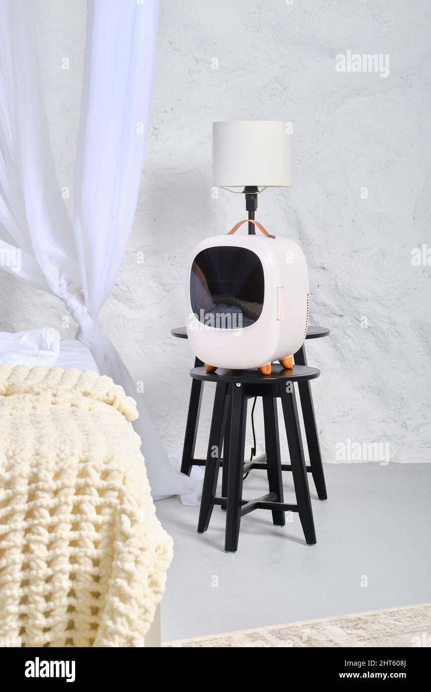 Compact and portable fridge on a chair near the bed in bedroom Stock ...