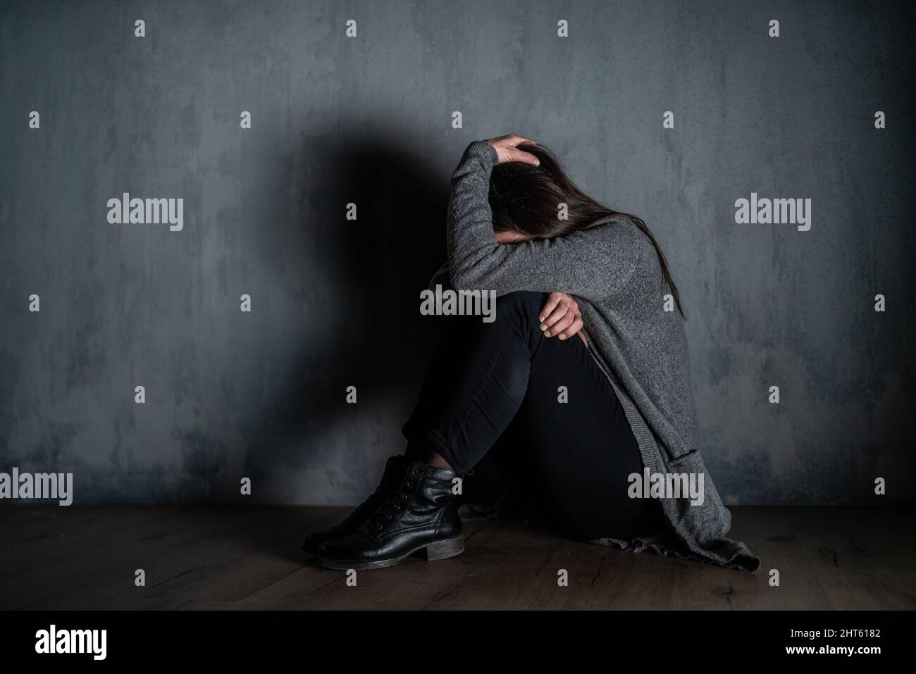 Sad mid-adult woman, alone in darkness, sitting and thinking Stock ...