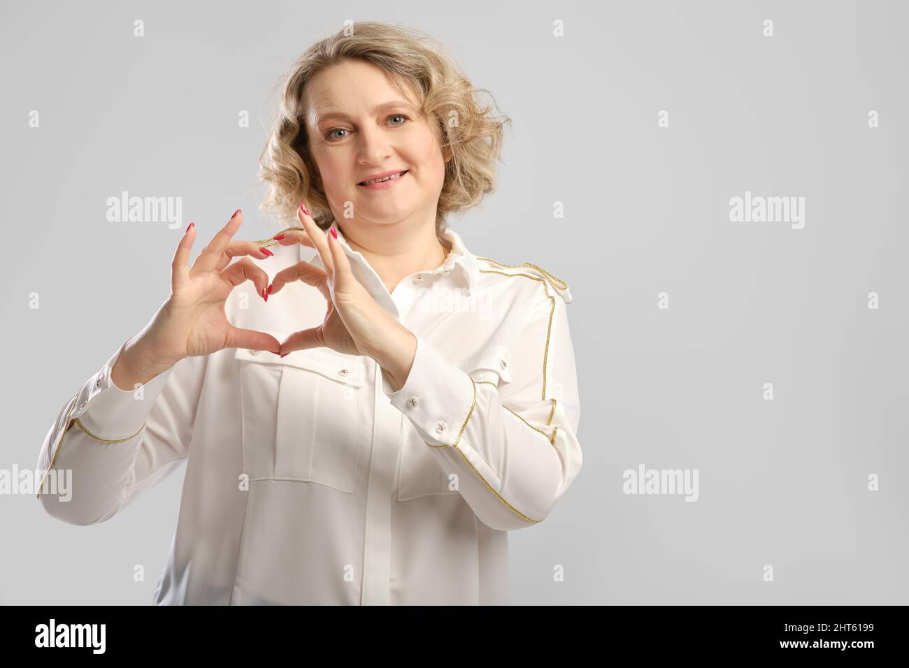 Happy senior woman shows love gesture. Middle aged woman folded palms ...