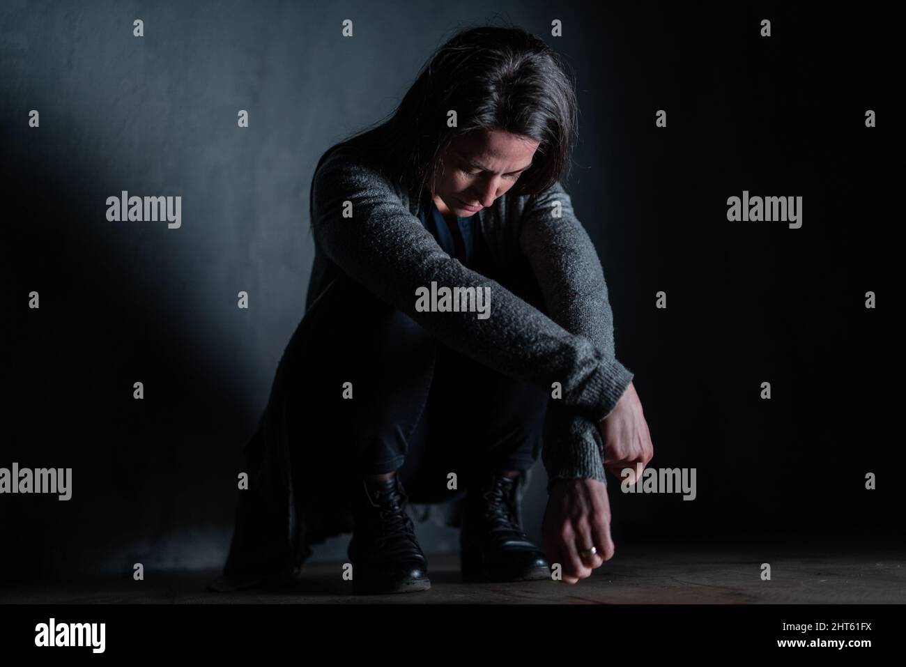Sad mid-adult woman, alone in darkness, sitting and thinking Stock ...