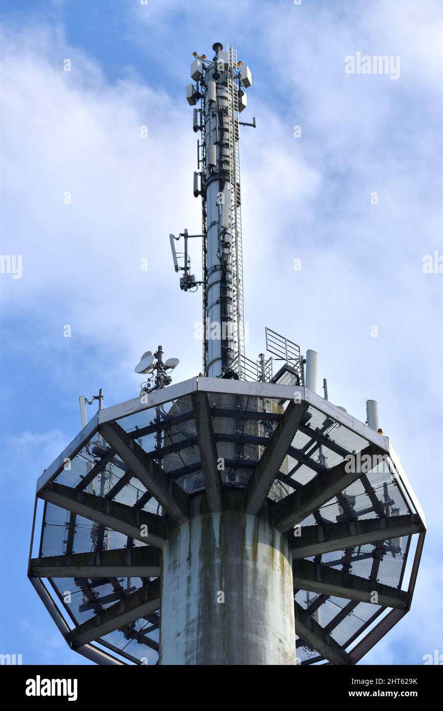 Vertical shot of a telecommunications tower against the blue cloudy sky ...