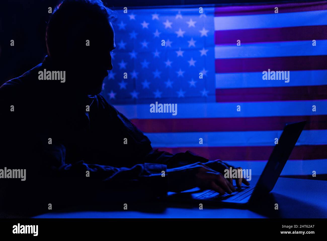 Hacker with laptop and USA flag in background. Cyber attack concept ...