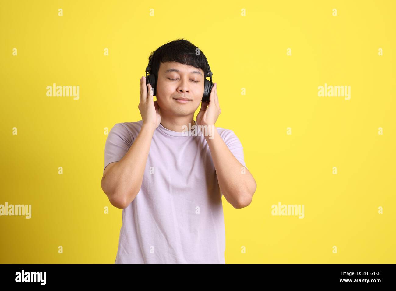The young adult Asian man standing on the yellow background Stock Photo ...
