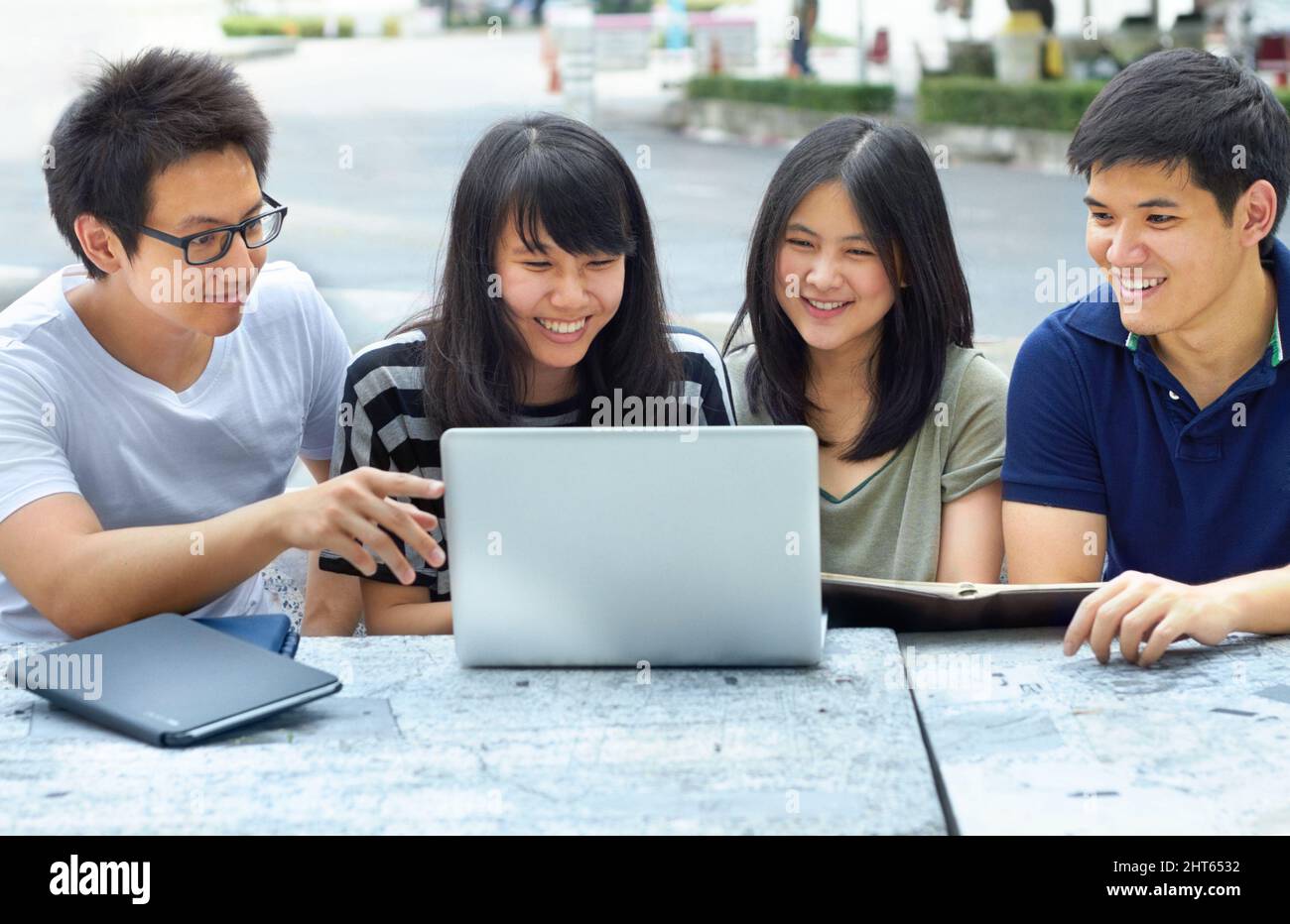 Studying outside. Four young students sharing a laptop outside Stock ...