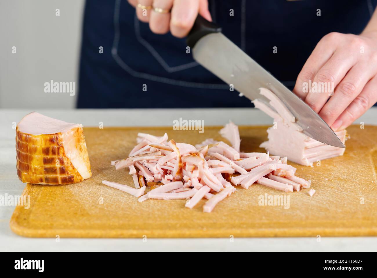 a woman's hand cuts a juicy piece of ham into pieces. wife cooks ...
