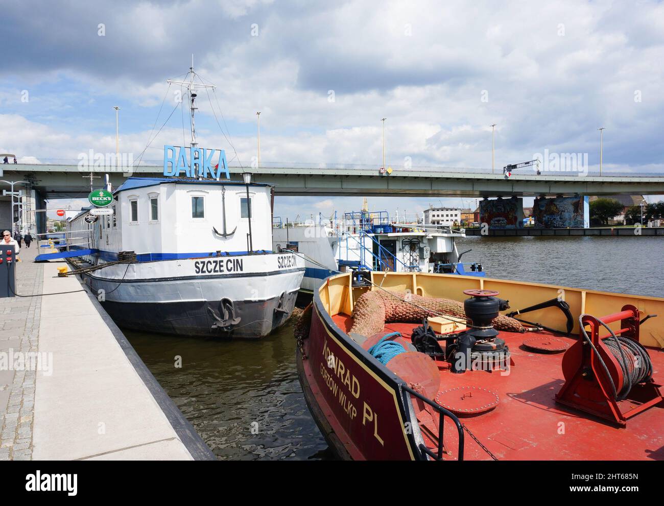 The two boats tied with ropes at a harbor against a blue sky in ...
