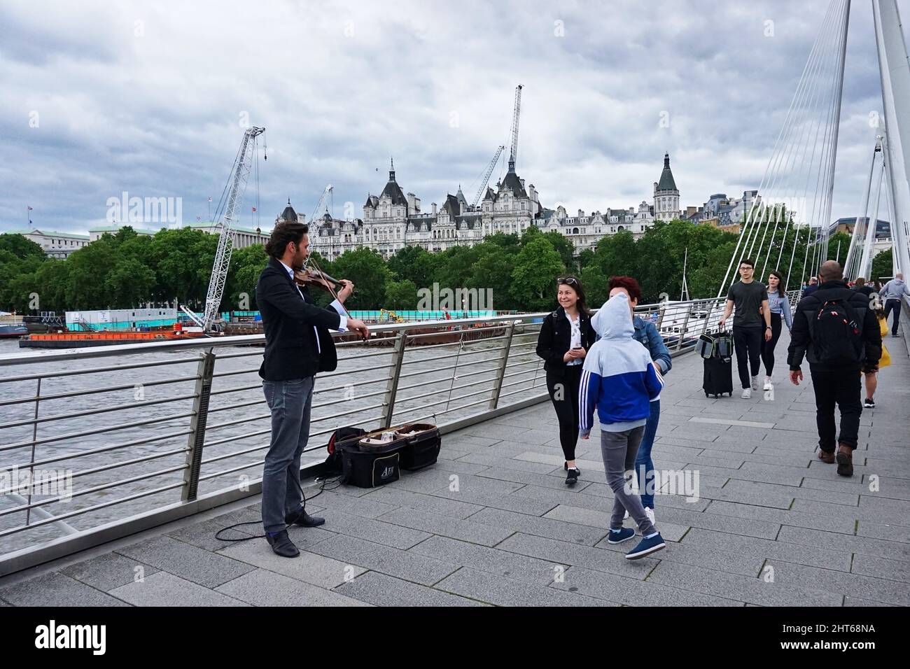 Street performer, the violinist playing on the Hungerford Bridge ...