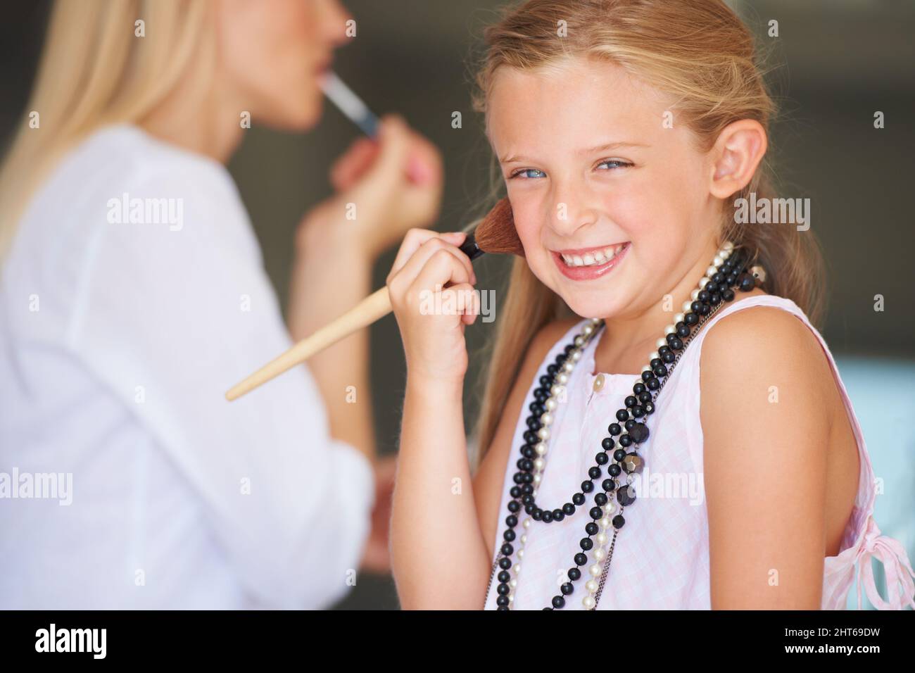Putting on make-up like mum. Little girl trying on her mothers makeup ...