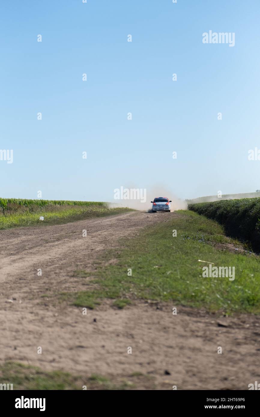 Vertical shot of the road, agriculture fields and the rally car driving ...