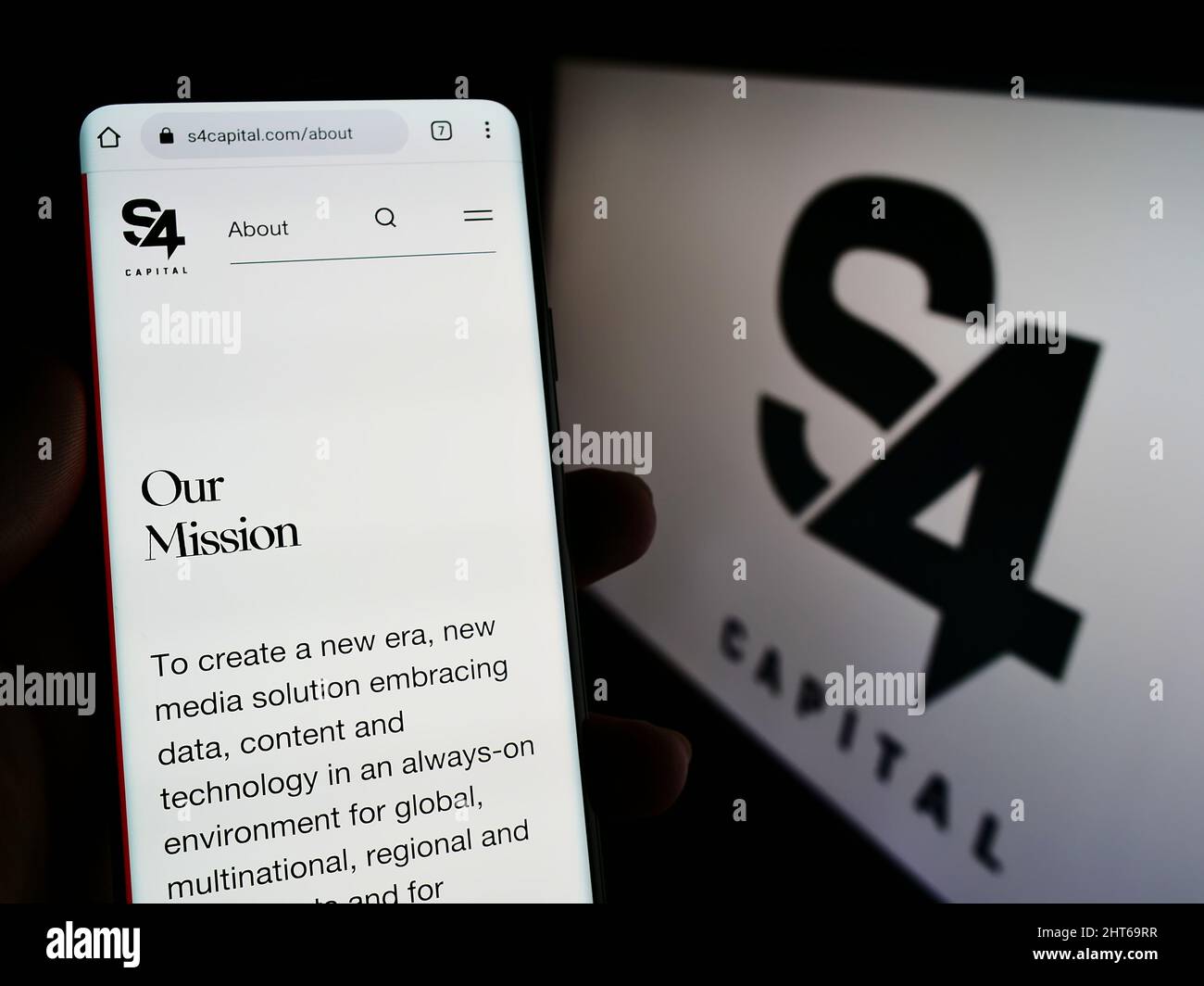 Person holding cellphone with website of British advertising company S4 ...