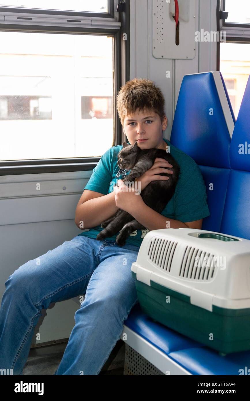 A teenager rides a train with a pet carrier Stock Photo - Alamy