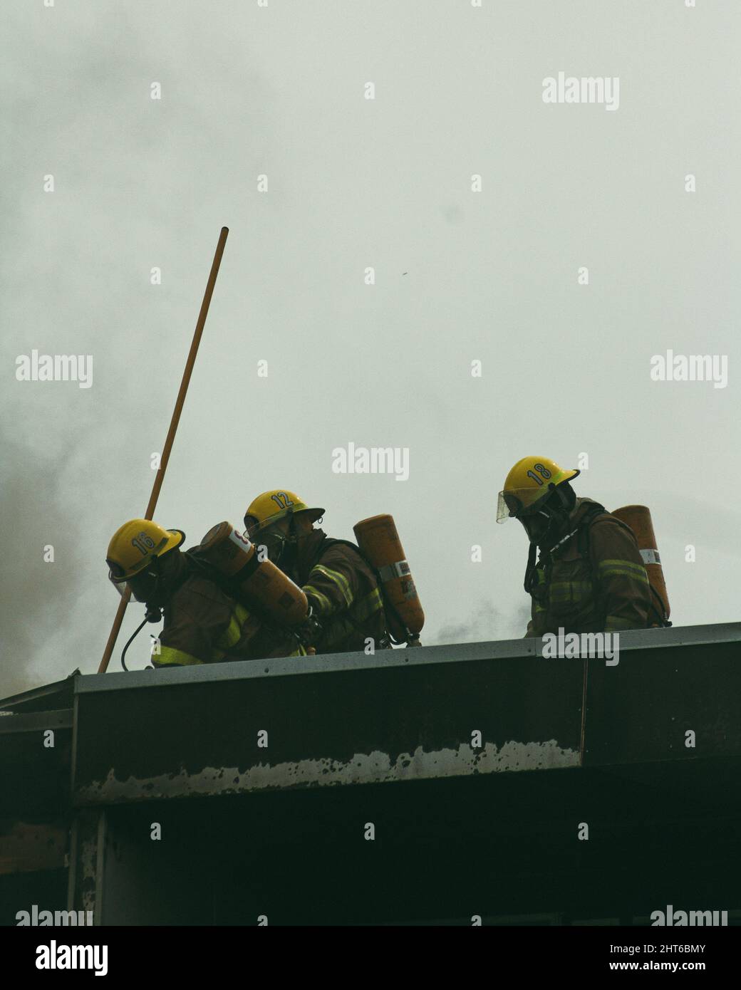 Photo of firefighters extinguishing a fire on a roof of a building and ...