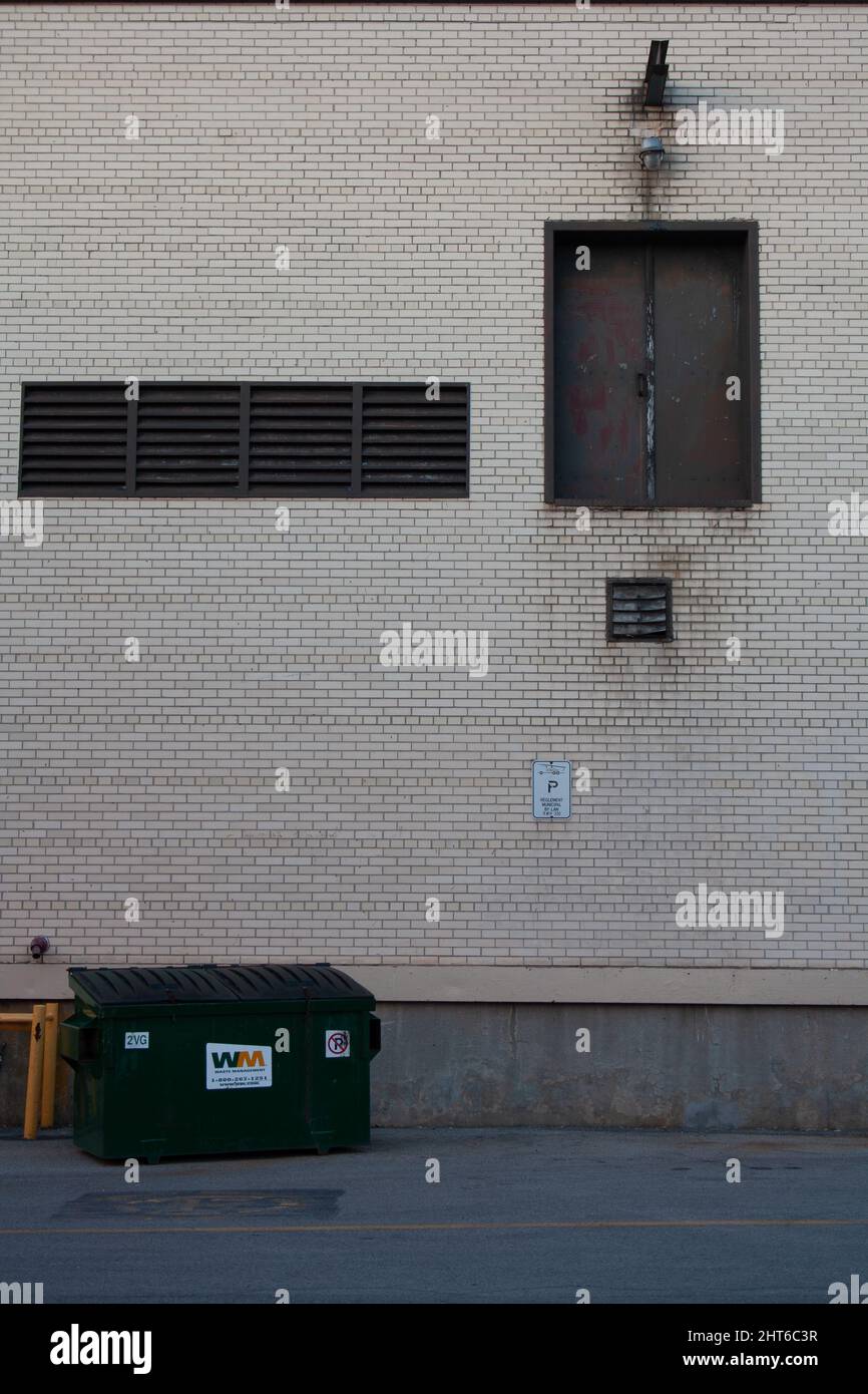 Vertical photo of a dumpster in a yard near a building Stock Photo - Alamy