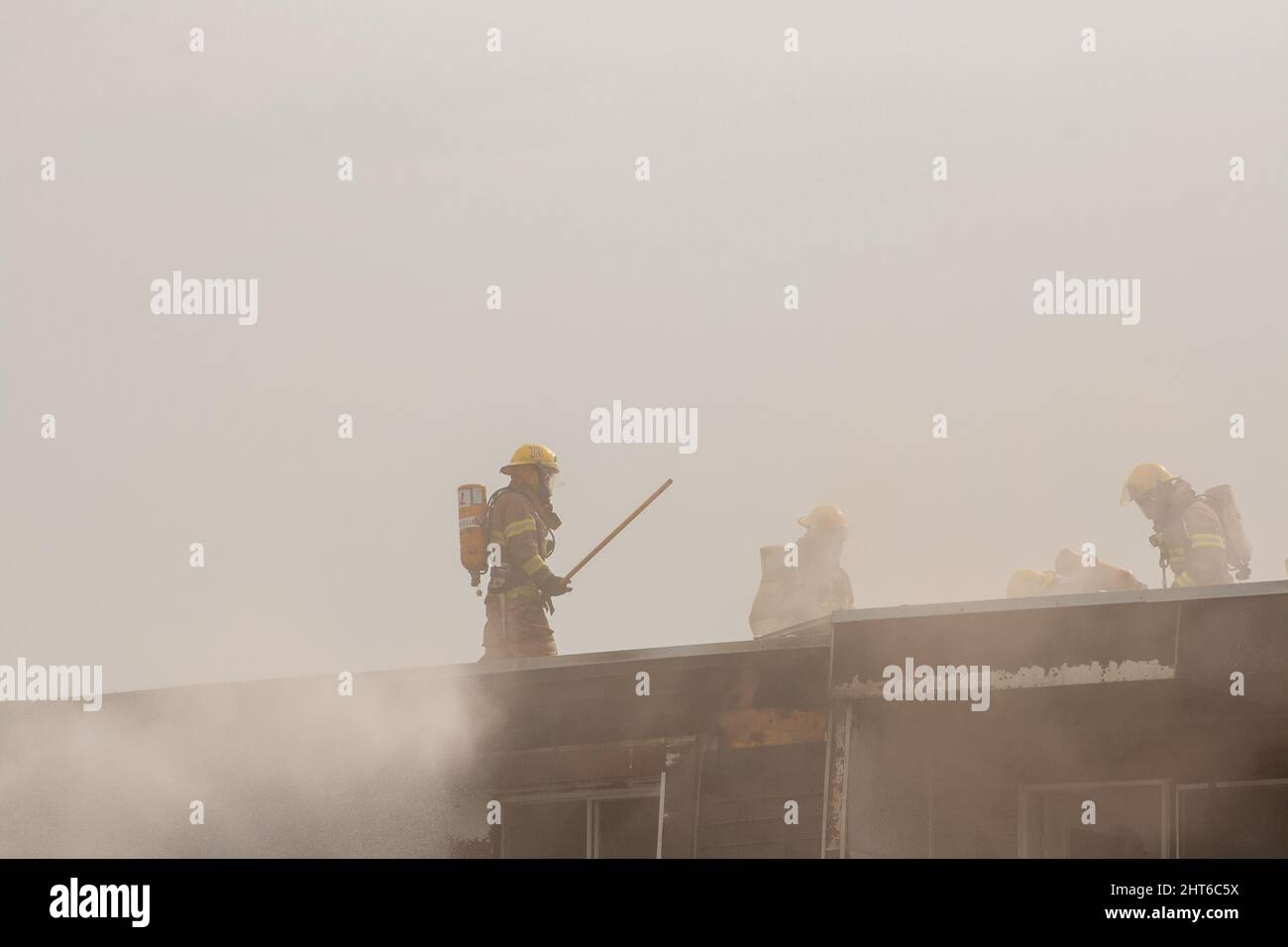 Photo of firefighters extinguishing a fire on a roof of a building and ...