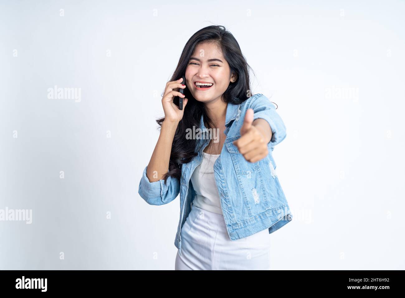Young asian woman making a call using a mobile phone with thumbs up ...