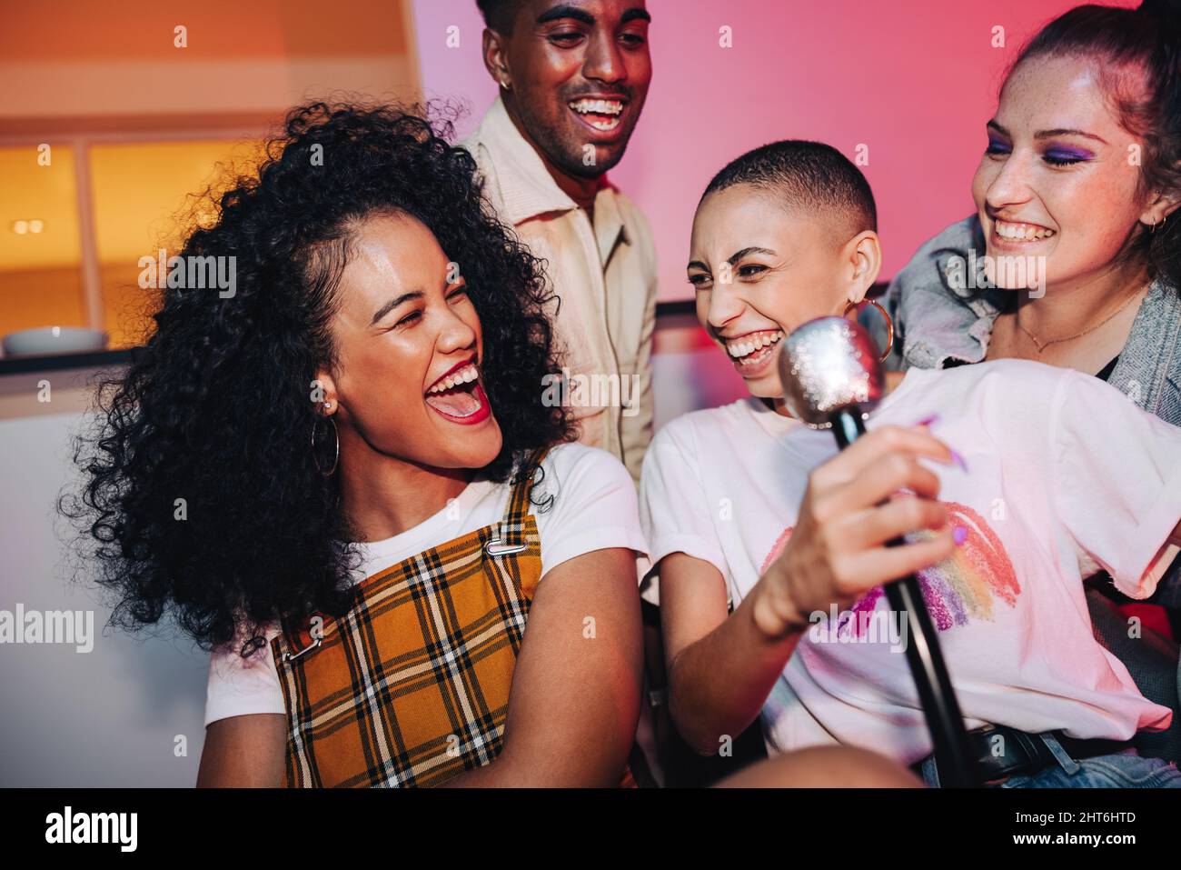 Ecstatic friends enjoying karaoke night. Happy young friends laughing ...