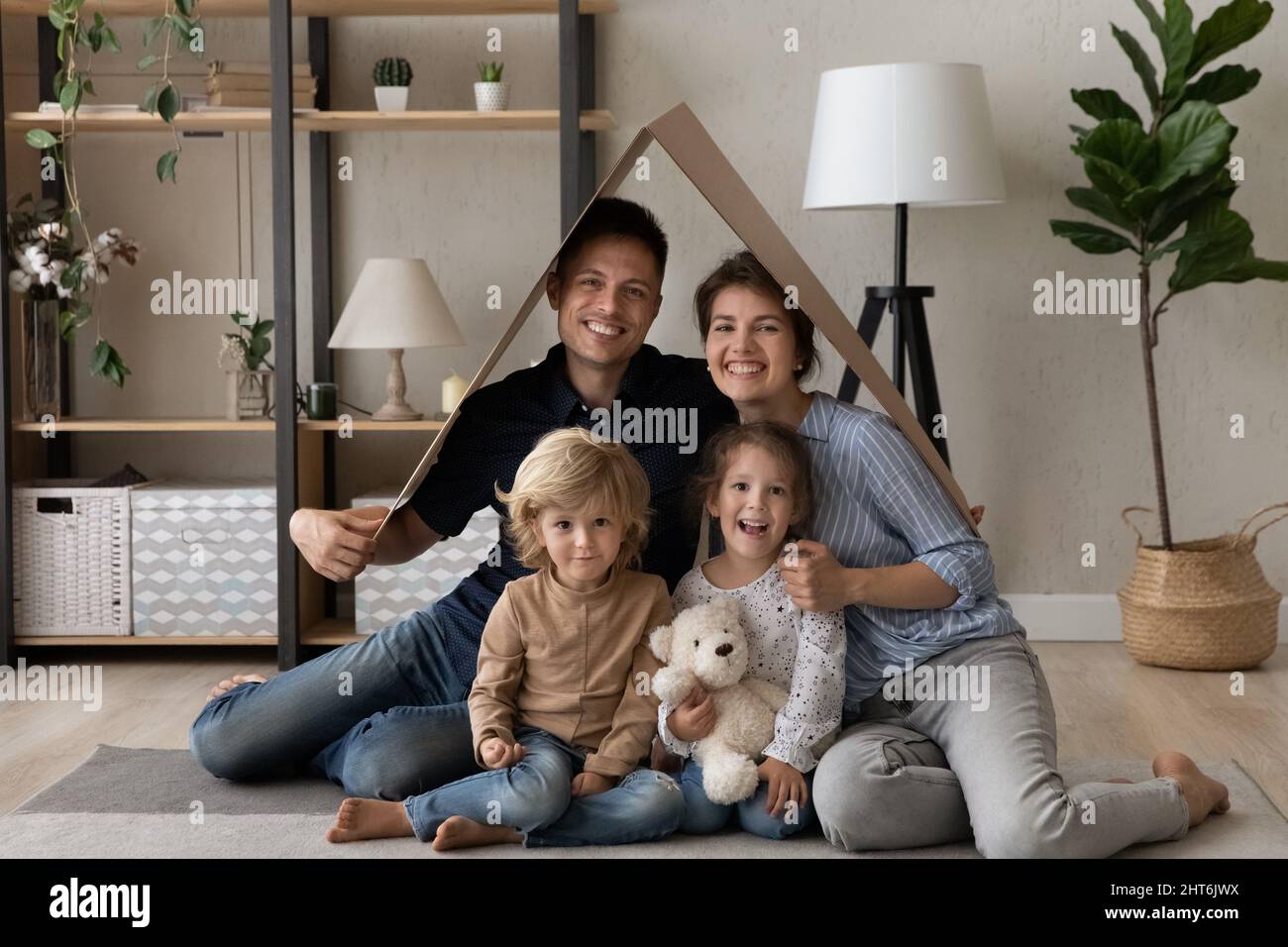 Portrait of smiling family sitting under carton roof Stock Photo - Alamy