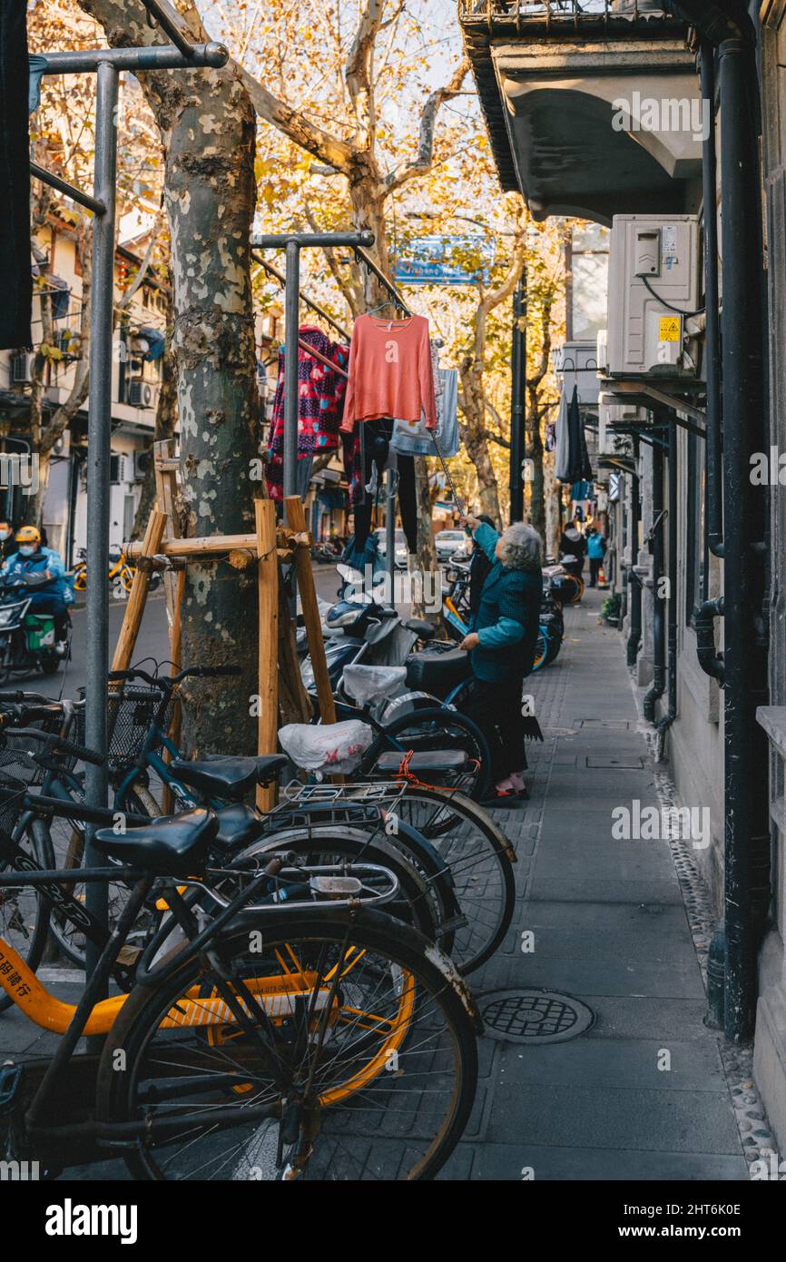Vertical shot of an Old woman spreading laundry in street in shanghai ...