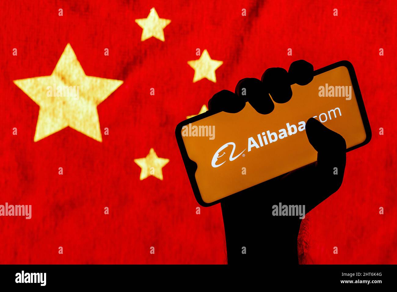 A smartphone with the Alibaba Group logo in a clenched hand on the ...