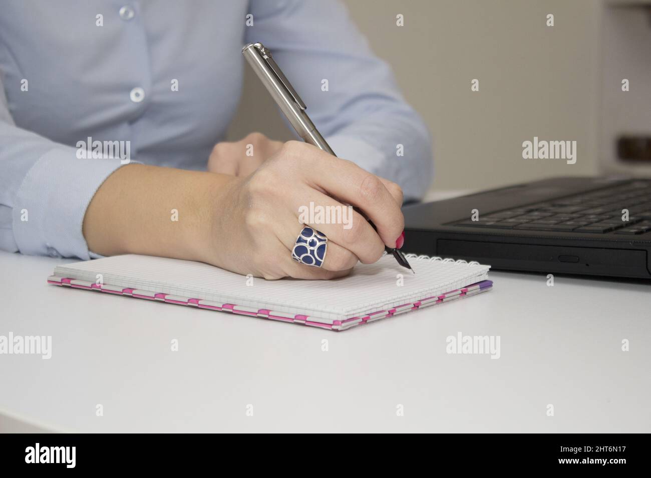 Closeup of the woman's hand taking notes while working with the laptop ...