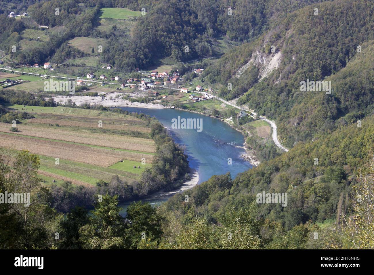 River flowing between an agricultural field and a dense forest on a ...