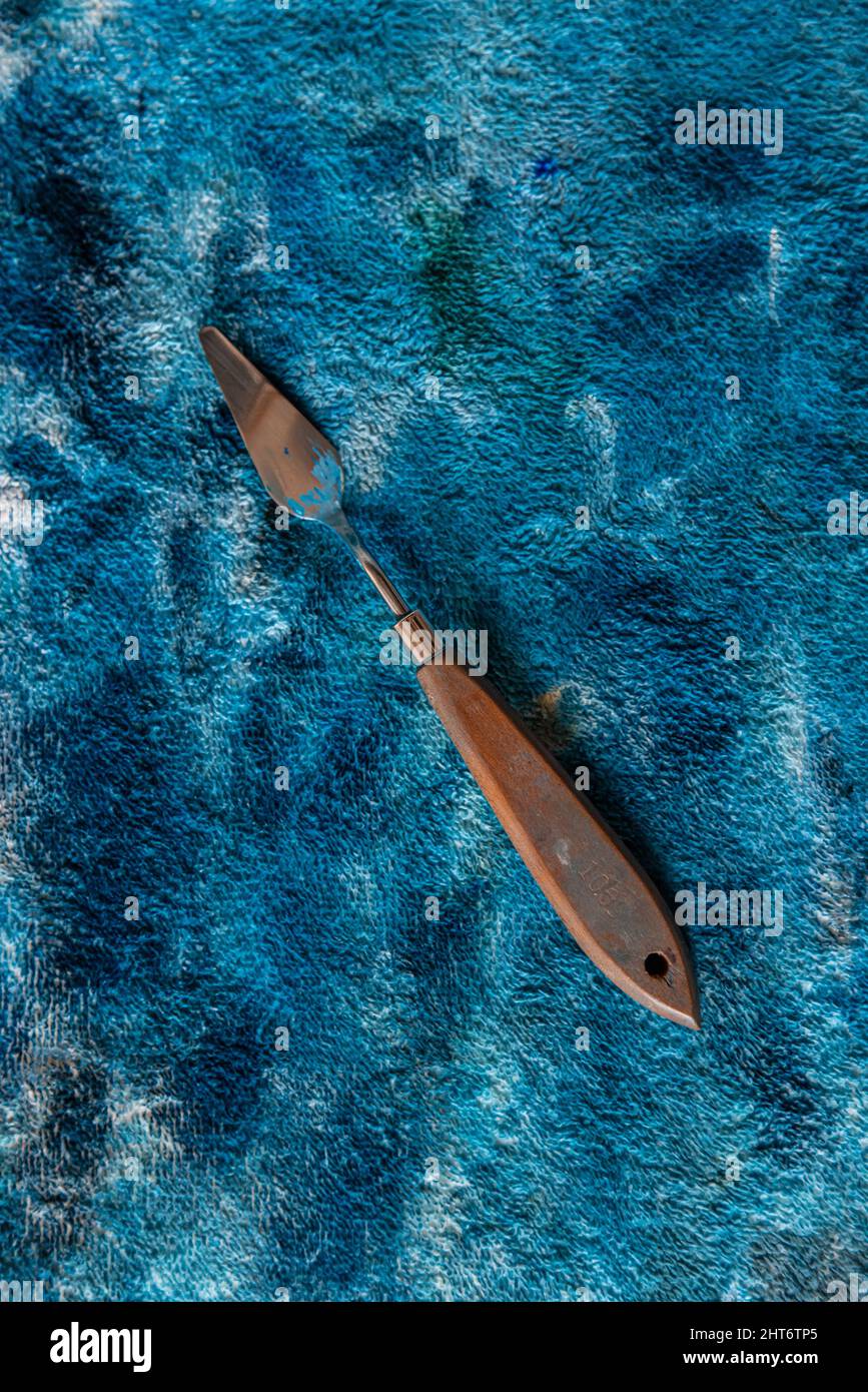 Vertical closeup of a pallet knife with stains of blue paint on the ...