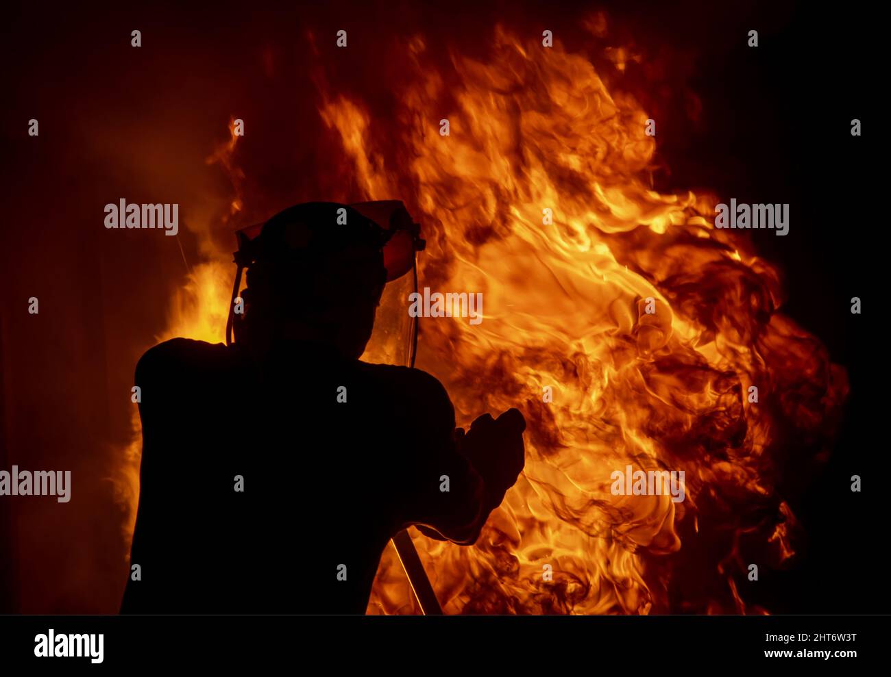 Back view of a firefighter extinguishing fire Stock Photo - Alamy