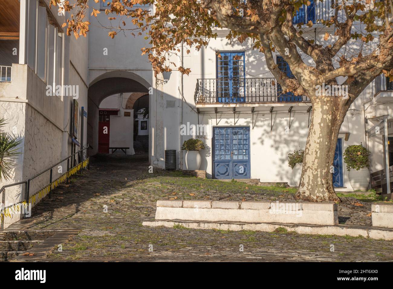 A facade showing an entrance to the town center and a tree in Cadaques ...