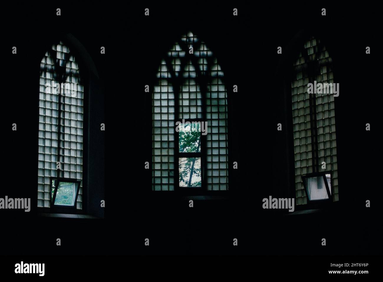 View of three gothic windows of a building, a dark room during daytime ...