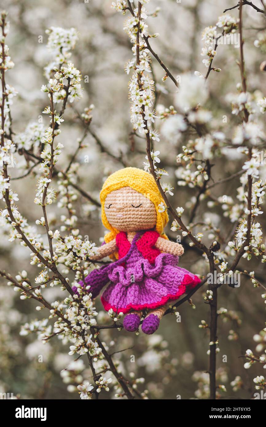 Product vertical photo of a handmade crochet doll on a branch of cherry ...