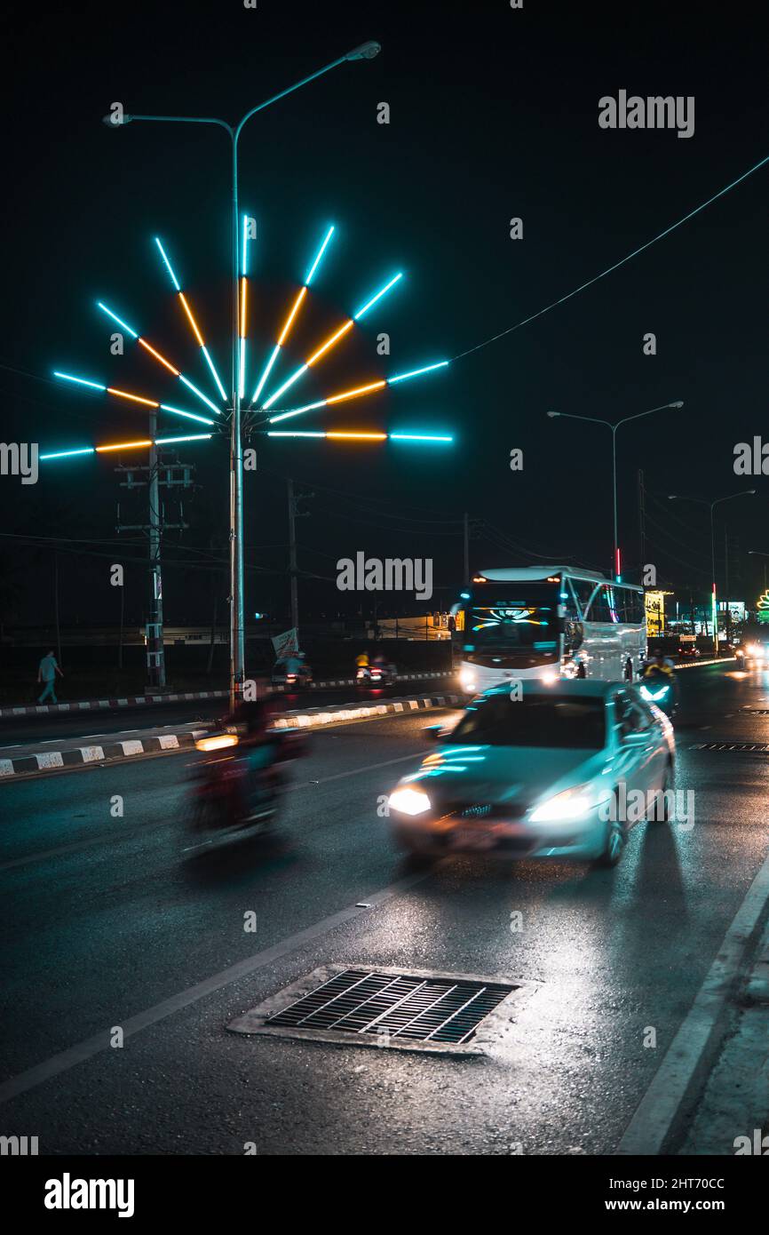 View of cars, bus and motorcycle on an asphalt road with neon lights on ...