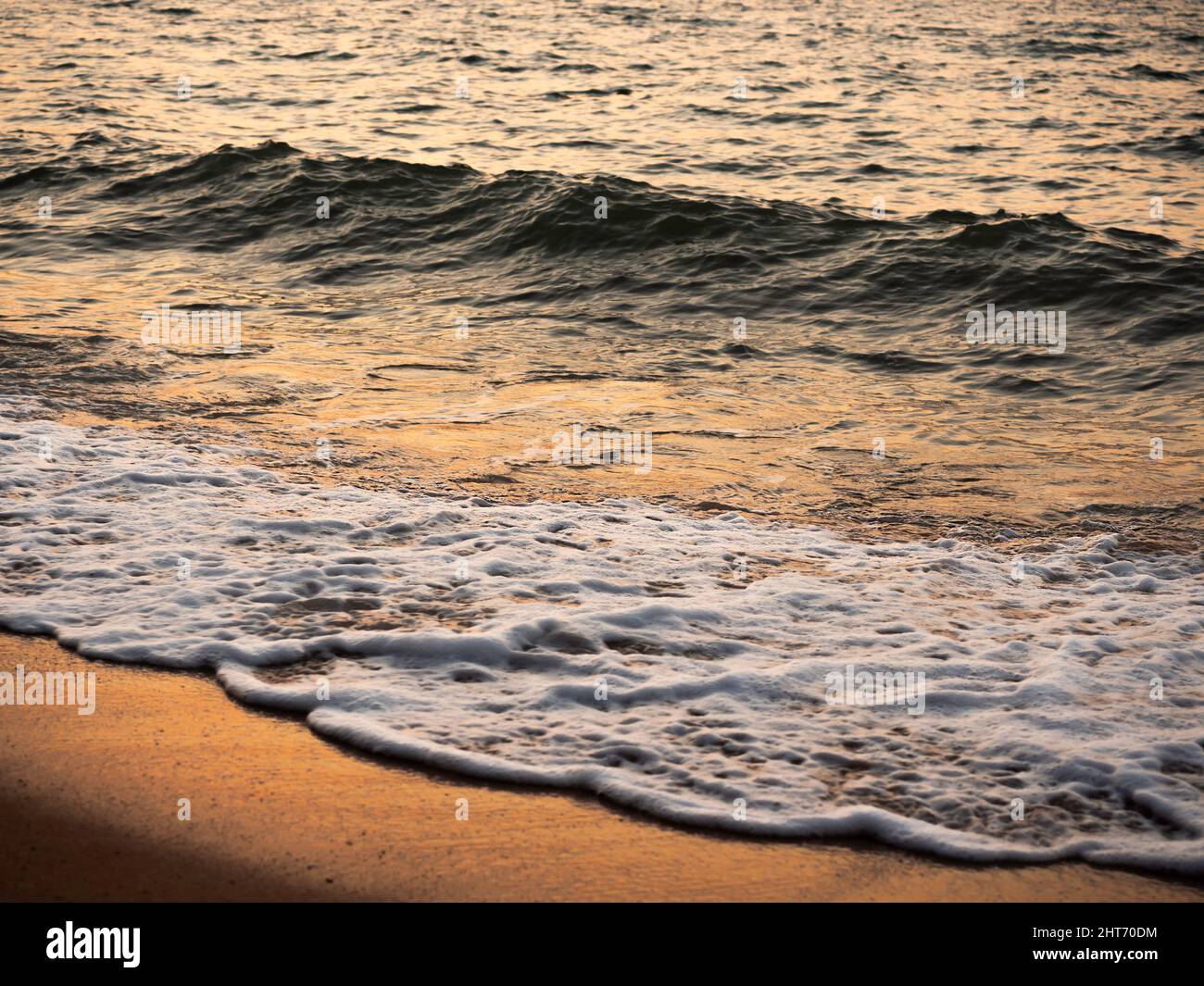 Blurred splashing sea wave on sand beach with beautiful golden sunset ...